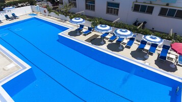 Piscina no terraço com água azul, rodeada por espreguiçadeiras e guarda-sóis.