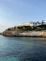 Hotel à beira-mar com fachada branca, várias varandas e vista para o mar.