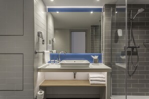 Uma casa de banho moderna com uma grande pia, espelho e chuveiro.