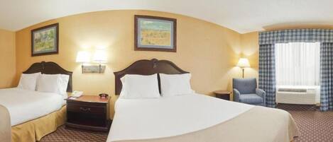 Quarto de hotel com duas camas, uma cadeira, uma escrivaninha e uma janela com cortinas.