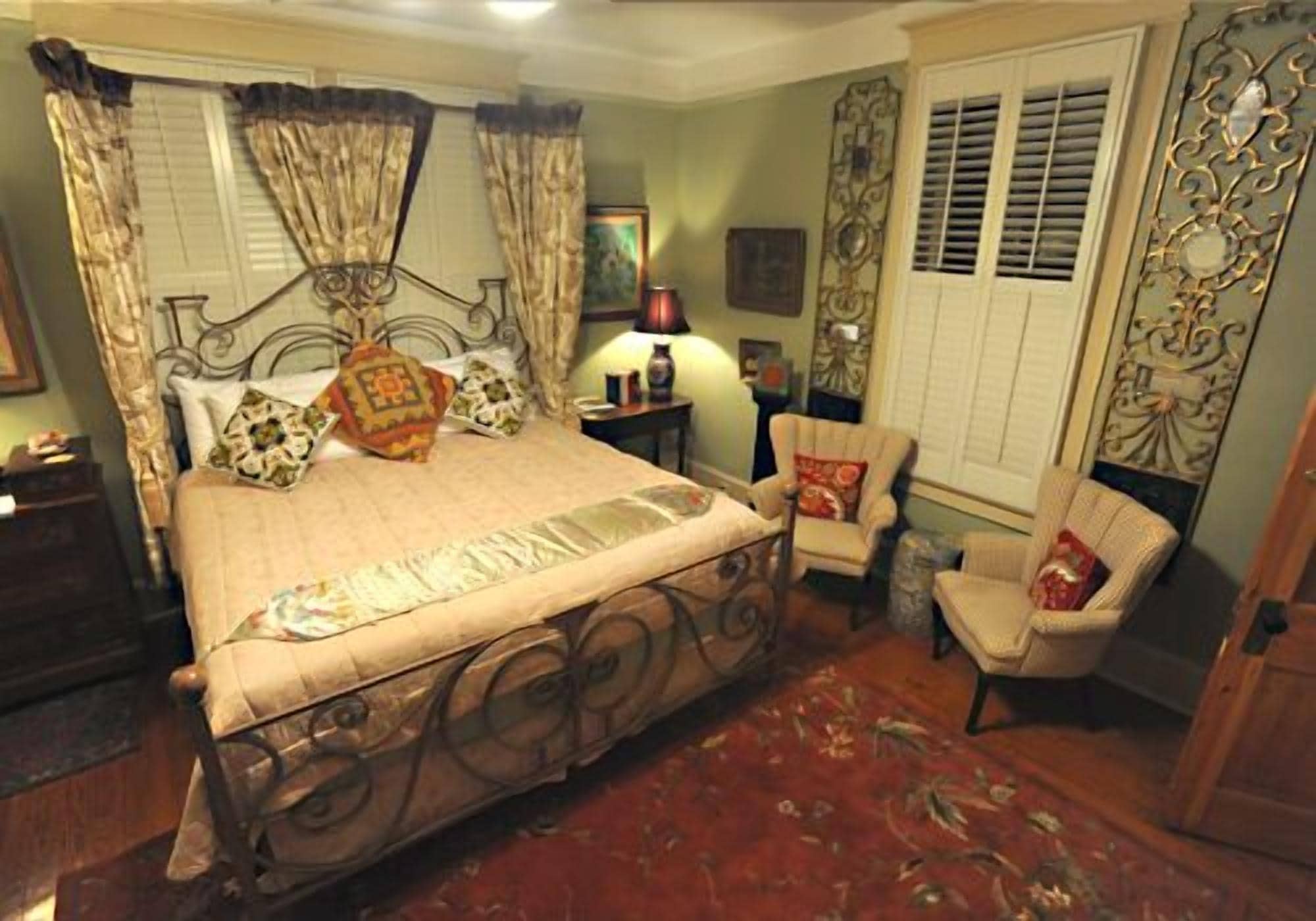 Quarto com cama, cadeira, mesa de cabeceira e janela com persianas.