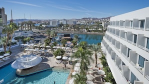Resort com piscina, palmeiras e vista para a cidade.