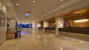 Um hall amplo com balcão de atendimento, área de estar e piso de mármore polido.