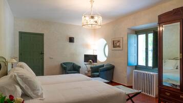 Quarto de hotel com duas camas, um candelabro, uma televisão e um espelho grande.