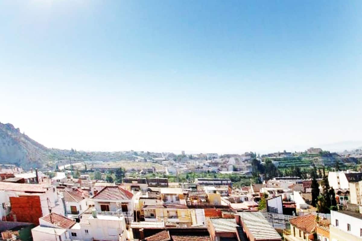 Uma área urbana densamente povoada, com edifícios e uma montanha imponente ao fundo.