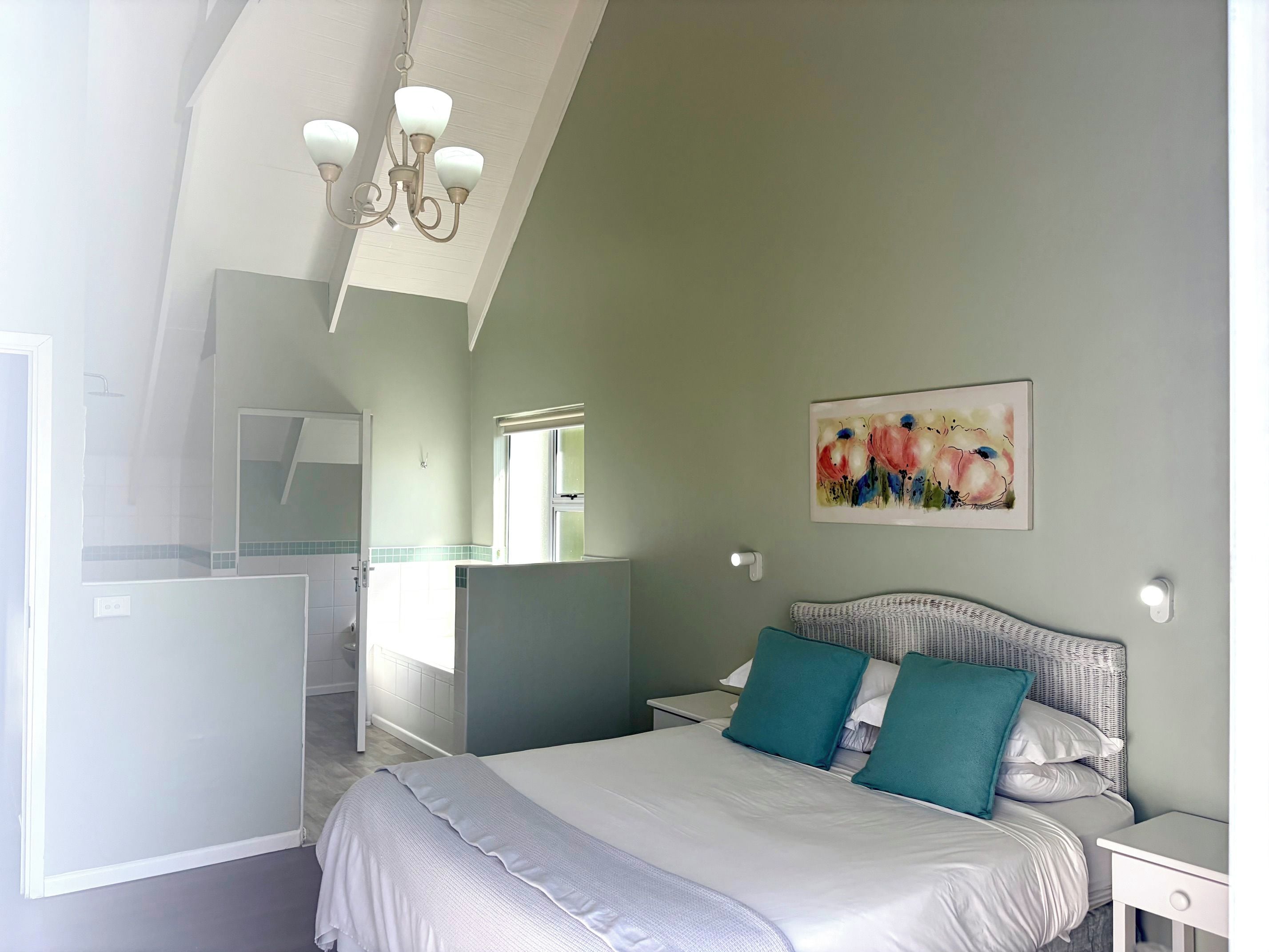 Quarto com cama, mesas de cabeceira, um candelabro, um quadro e uma janela.
