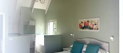 Quarto com cama, mesas de cabeceira, um candelabro, um quadro e uma janela.