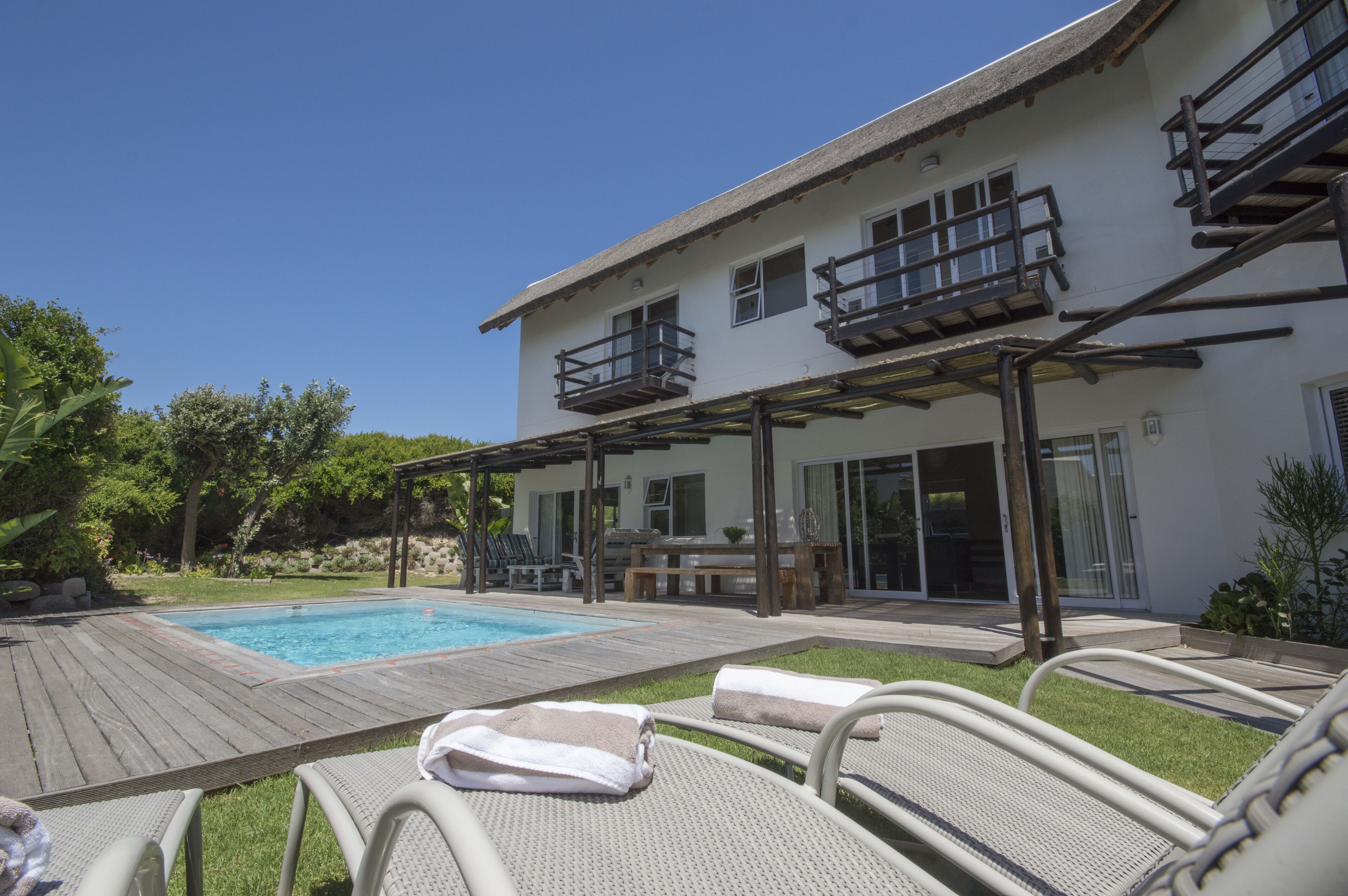 Área de piscina com espreguiçadeiras e um pérgola.