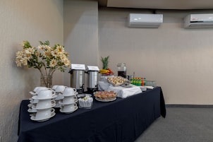 Disposição de buffet com estações de café e chá, uma fruteira e um dispensador de água.