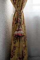 Cortina com padrão floral e um franjário pendurado.