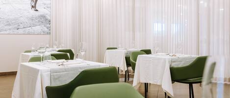 Restaurante com várias mesas, cada uma com toalhas brancas e cadeiras verdes.