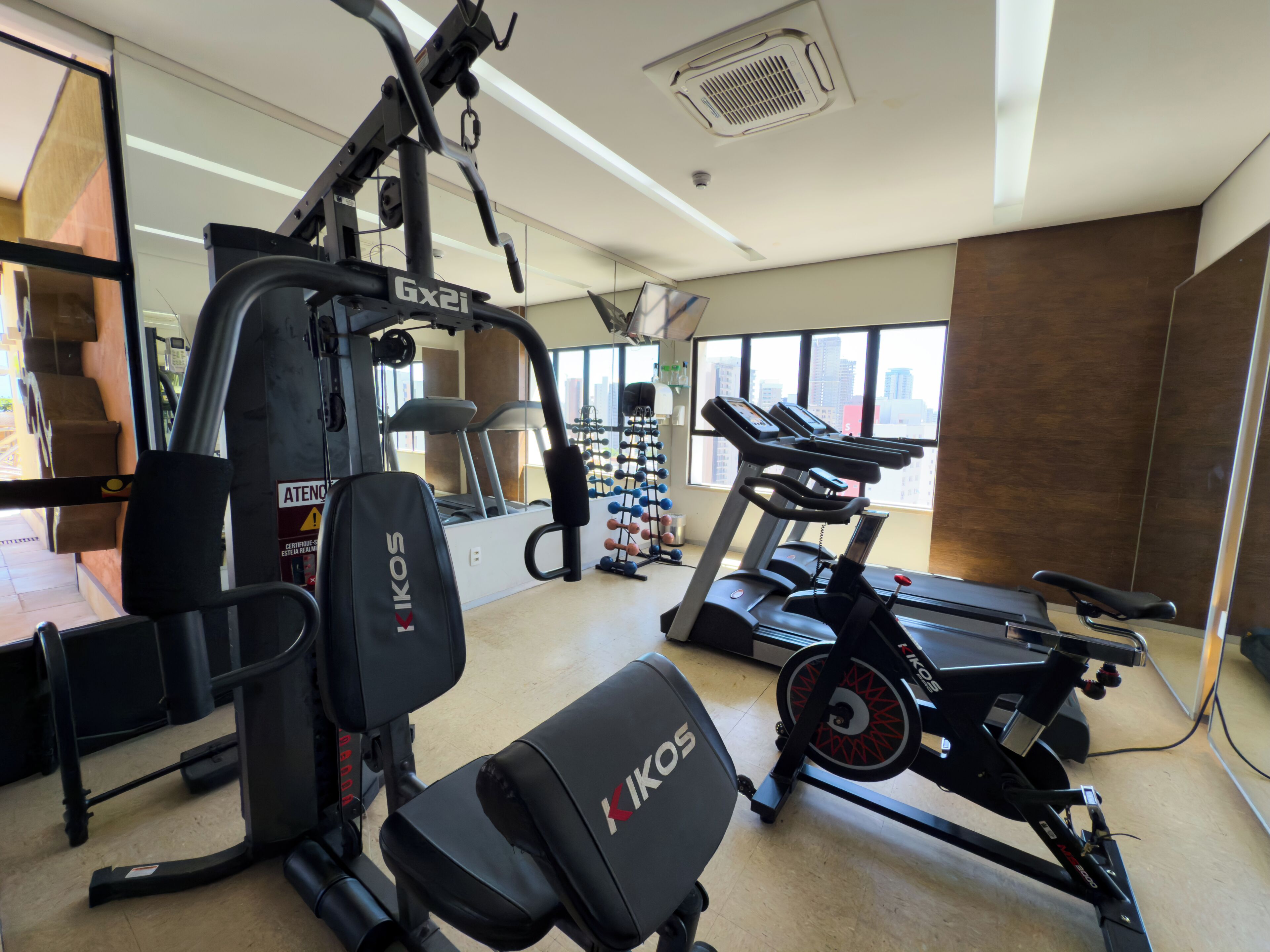 Uma academia com máquinas de cardio, equipamentos de musculação e esteira.