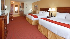 Quarto de hotel com duas camas, uma escrivaninha, uma cadeira, televisão e banheiro.