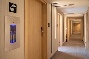Corredor de hotel com portas de madeira, bebedouro e extintor de incêndio.
