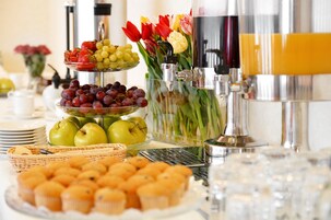 Uma mesa de buffet com diversos alimentos, incluindo frutas, legumes e doces.