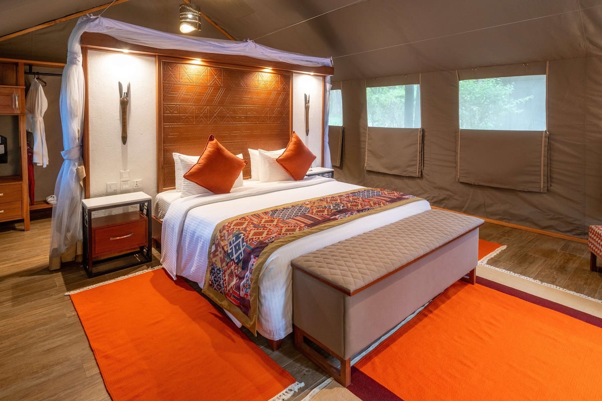 Quarto em estilo de tenda, com cama, mesas de cabeceira e uma janela.