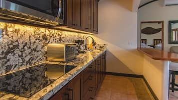 Uma cozinha com bancada de granito, micro-ondas embutido e armários de madeira.