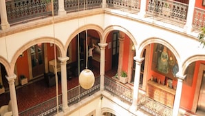 Um átrio com vários níveis, com passarelas em arco, lanternas penduradas e um mural no nível superior.