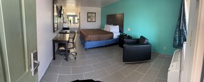 Quarto de hotel com cama, escrivaninha, cadeira, sofá e banheiro.