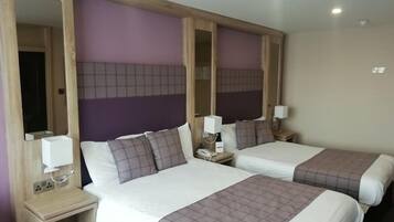 Quarto de hotel com duas camas, cada uma com mesa de cabeceira, espelho e luminária.