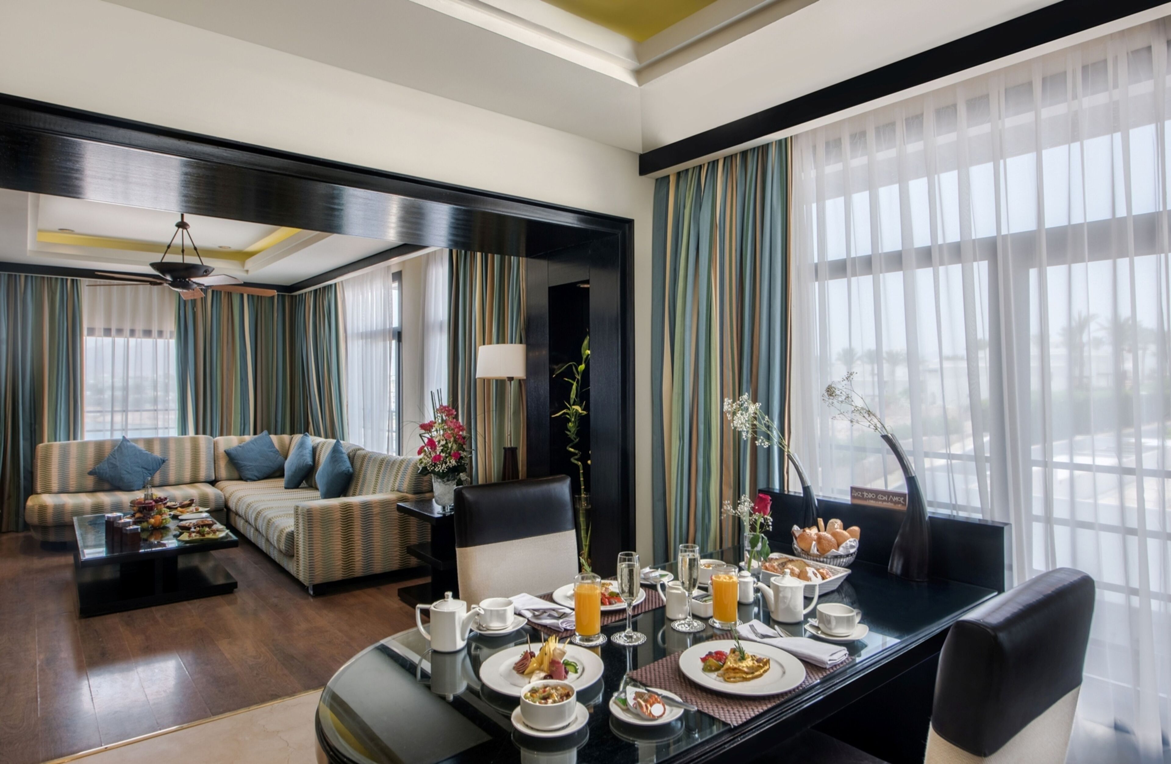 Quarto de hotel com área de refeições, sofá e vista para o exterior.