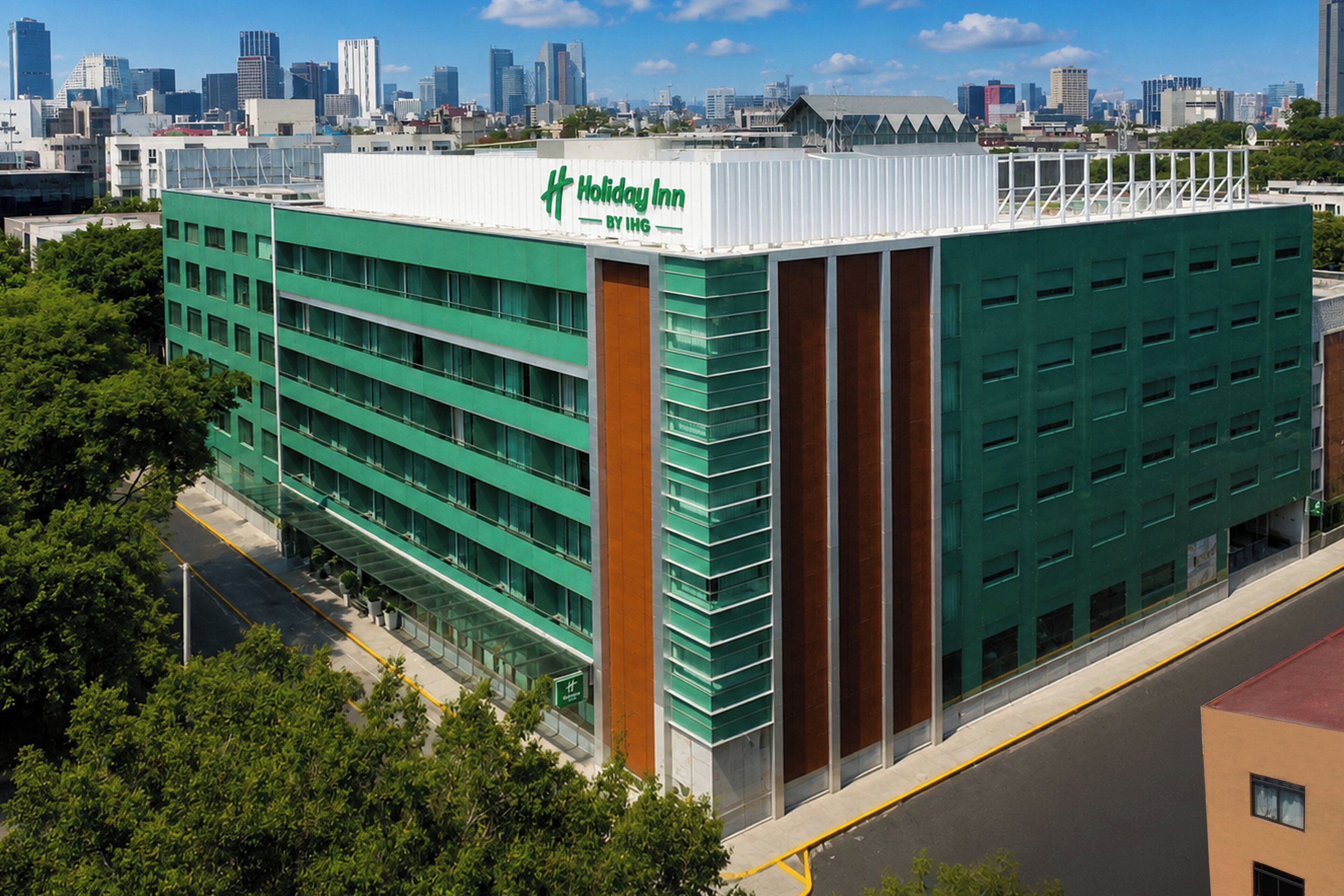 Um hotel Holiday Inn com design moderno, destacando uma fachada verde e um terraço no terraço.