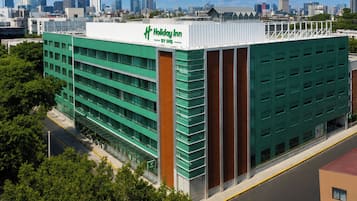 Um hotel Holiday Inn com design moderno, destacando uma fachada verde e um terraço no terraço.