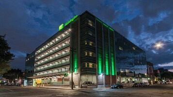 Um hotel Holiday Inn de vários andares, com design moderno, exibindo uma grande placa 'Holiday Inn' no telhado.