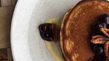 Uma pilha de panquecas com calda e nozes pecan.