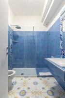 Uma casa de banho com chuveiro, sanita e lavatório.