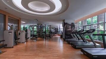 Uma academia com esteiras, aparelhos de musculação e equipamentos de cardio.
