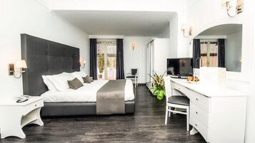 Quarto de hotel moderno com uma cama grande, uma escrivaninha e uma televisão.