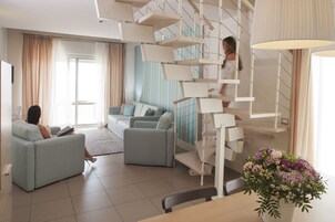 Uma sala de estar moderna com escada, um sofá e uma área de jantar.