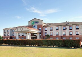 Edifício Holiday Inn Express & Suites com fachada de tijolos, diversas janelas e céu claro.