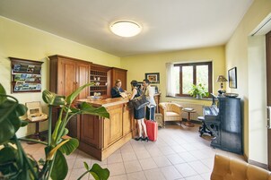 Um saguão de hotel com uma recepção de madeira, um quadro de avisos, uma janela ampla com vista e um fogão antigo.