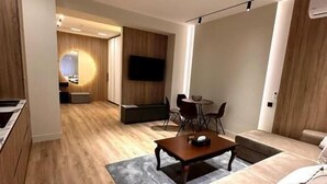Uma sala de estar moderna com um sofá, uma mesa de centro e uma televisão fixada na parede.