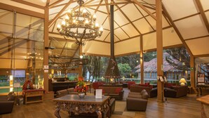 Um hall amplo com teto alto, lustre, assentos confortáveis e grandes janelas com vista para o exterior.