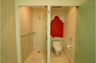 Casa de banho com cabine de duche em vidro, sanita e parede com detalhes em vermelho.
