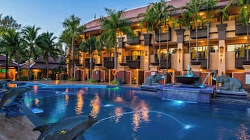 Um hotel com piscina, palmeiras e uma estátua de elefante.