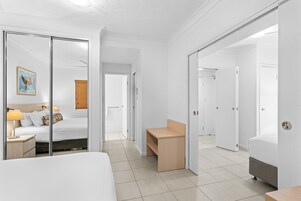 Quarto de hotel com cama, mesa de cabeceira, abajur e um quadro na parede.