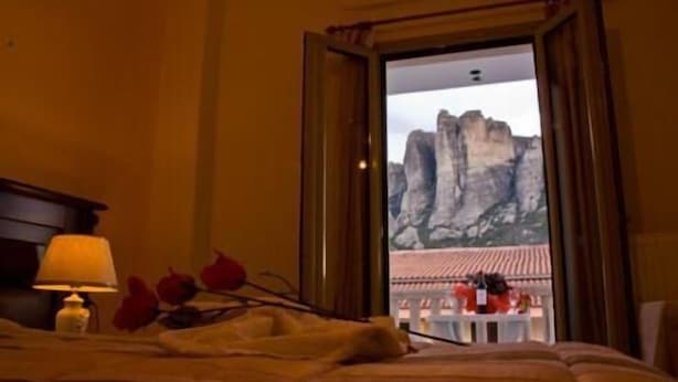 Quarto de hotel com uma cama, mesa de cabeceira e janela com vista para uma paisagem rochosa.