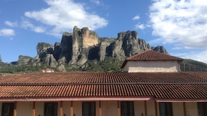 Um edifício com telhado ladrilhado e vista para uma montanha rochosa ao fundo.