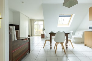 Uma sala de estar moderna com área de jantar, sofá, TV e cozinha com janela.