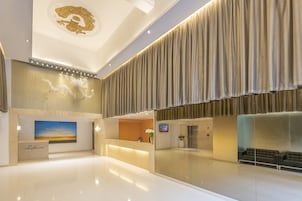 Um hall amplo com uma mesa de recepção, uma pintura grande e um design de teto moderno.