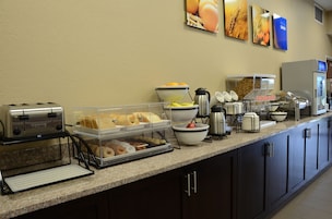 Disposição de buffet de café da manhã com diversos alimentos e eletrodomésticos.