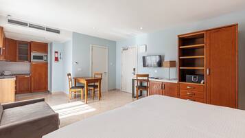 Quarto de hotel com cama, escrivaninha com cadeira, televisão, micro-ondas e guarda-roupa.
