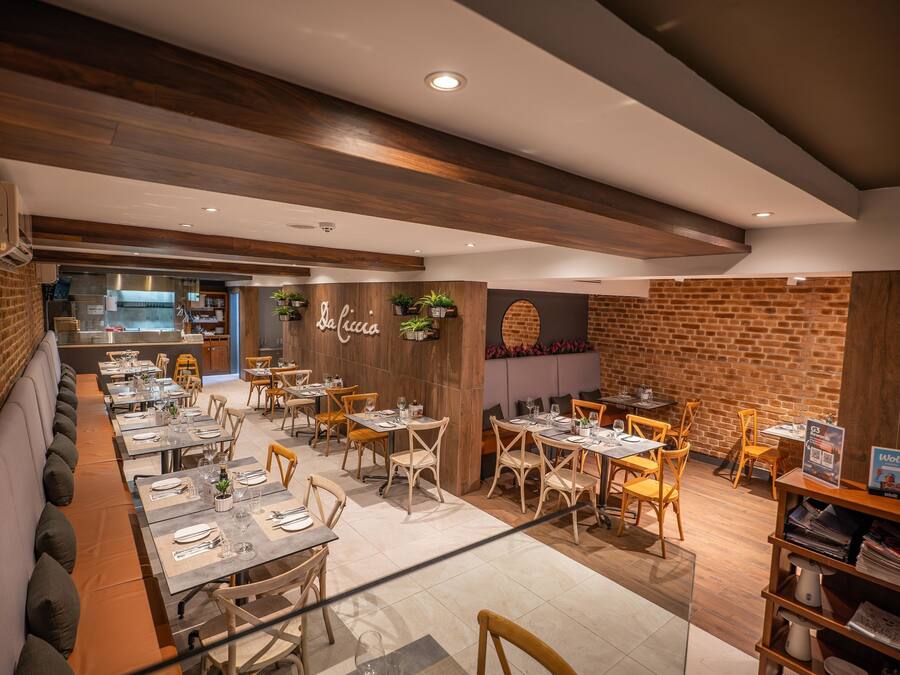 Restaurante com detalhes em madeira, paredes de tijolo e diversas opções de assento, incluindo mesas e cabines.