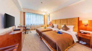 Quarto de hotel com duas camas, uma escrivaninha, uma televisão e uma janela com cortinas.