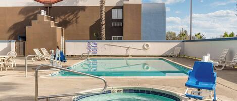 Piscina com hidromassagem, espreguiçadeiras e uma palmeira.