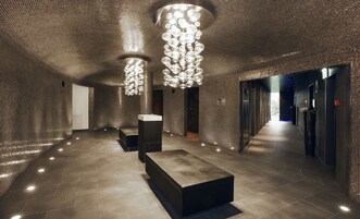 Um interior moderno com parede estampada, luminária central e um banco.